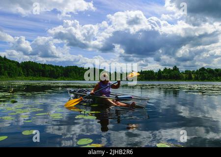 woman enjoying weekend rowing on transparent boat in small lake, bright ...
