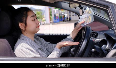Desperate woman hold cash dollar bills in to car with an open tank ...
