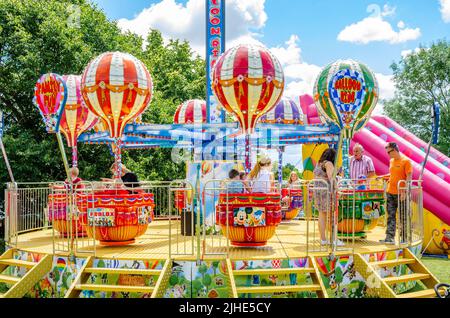 A children's fairground ride with carriages with balloons which spin ...