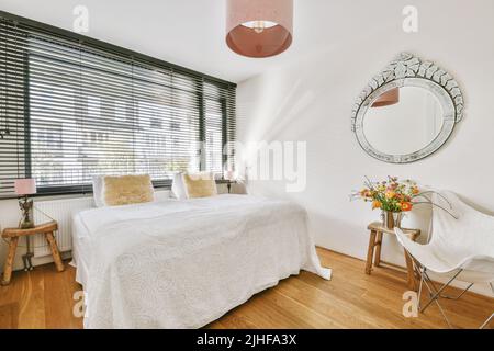 Comfortable bed located near window with curtain in light bedroom of ...