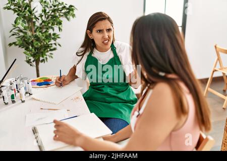 Couple of art students sitting at the table while painting together ...