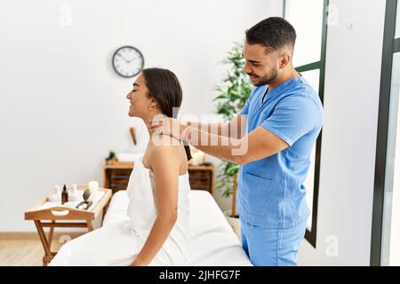 Latin man and woman wearing physiotherapy uniform having rehab session ...