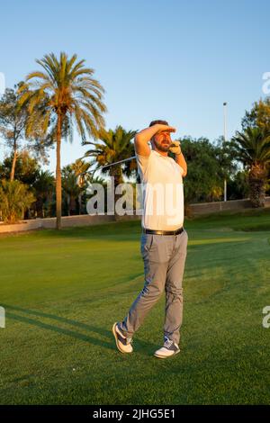 Good strike, golfer swinging his driver and looking away while standing ...
