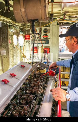 Man, engineer, oiling a large diesel engine in the engine room of the ...