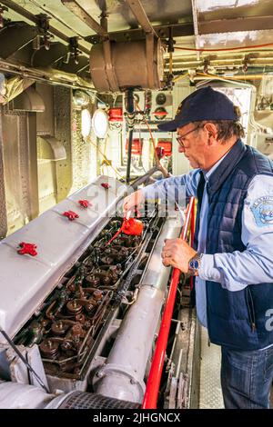 Man, engineer, oiling a large diesel engine in the engine room of the ...