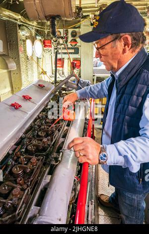 Man, engineer, oiling a large diesel engine in the engine room of the ...