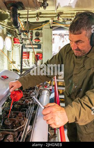 Man, engineer, oiling a large diesel engine in the engine room of the ...
