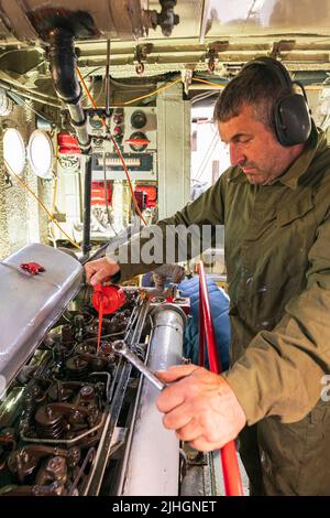 Man, engineer, oiling a large diesel engine in the engine room of the ...