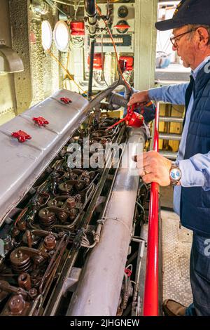 Man, engineer, oiling a large diesel engine in the engine room of the ...
