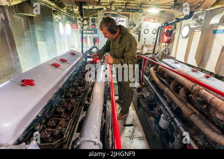 Man, engineer, standing between two large diesel engines, while oiling ...