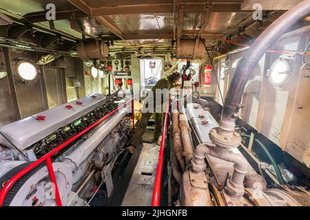 Man, engineer, standing between two large diesel engines, while oiling ...