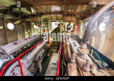 Man, engineer, standing between two large diesel engines, while oiling ...