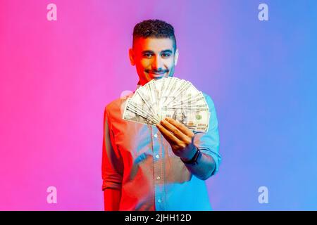 Handsome latin man holding dollars banknotes surprised with an idea or ...