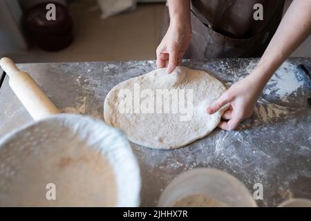 A baker shapes and cuts traditional French Fougasse bread. Front view ...