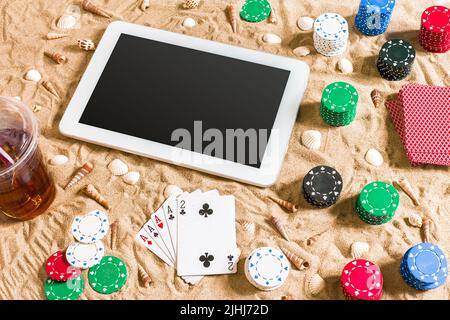 Online poker game on the beach with digital tablet and stacks of chips ...