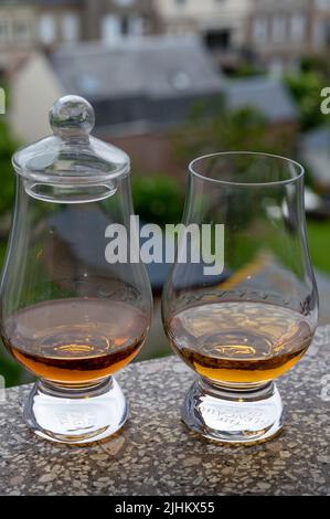 Two drams of scotch whiskey with view on old houses on background ...