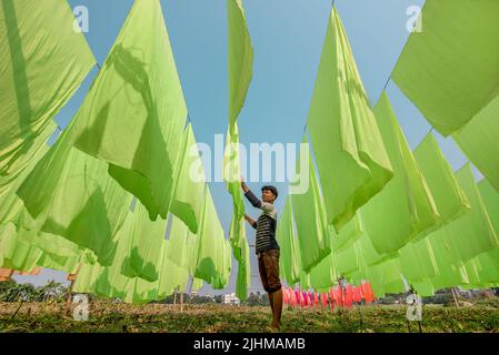 Colorful yarns and fabrics dyed and drying in open fields. Textile ...
