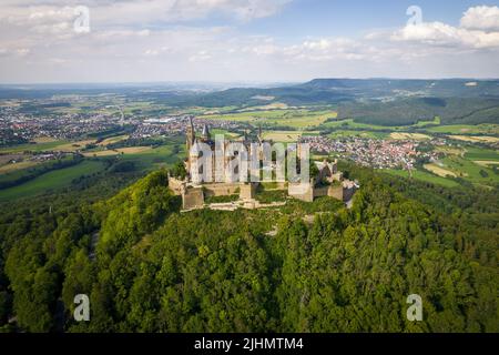 Drone shot of Hohenzollern Castle on forested mountain top in the ...