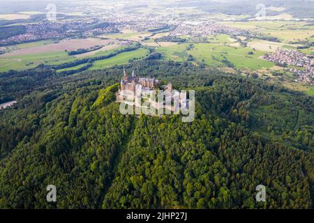 Drone shot of Hohenzollern Castle on forested mountain top in the ...