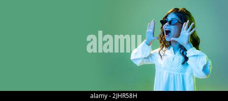 Thrilled little girl, kid shouting in rejoice and raising hands up ...