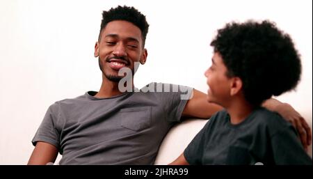 Older brother chatting with younger sibling. Candid mixed race two ...