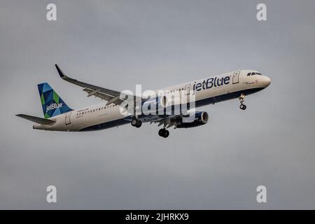 A Jetblue plane flying overhead before landing Stock Photo - Alamy