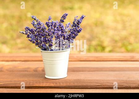 Purple lavender flowers collected in a white bucket on a wooden table ...