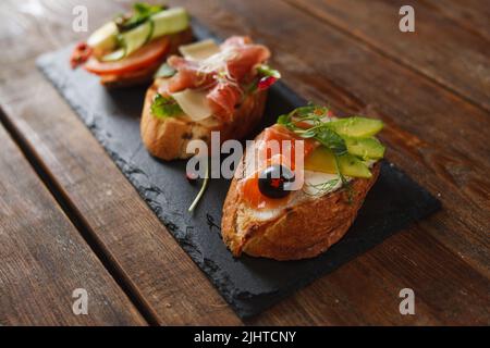 Small canapes laying on black tray Stock Photo - Alamy
