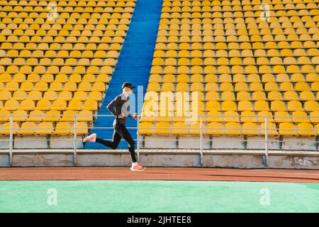 Young white sportsman running while working out on stadium outdoors ...