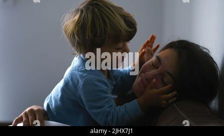 Little boy biting mother nose, real life authentic family moment at ...