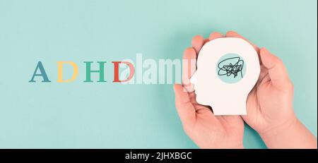 Hands holding a silhouette of a human head, attention deficit ...