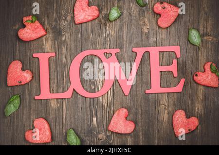 Watermelon hearts, wooden word love and basil leaves on light stone ...