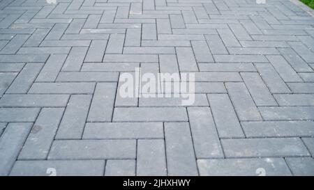 The principle of laying paving slabs. A worker spreads sand with a ...