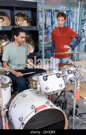 Customer standing near smiling seller and accessories in showcase in ...