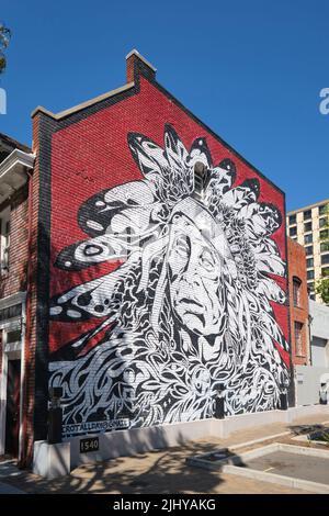 A huge mural on a red brick wall, featuring a portrait of a legendary ...
