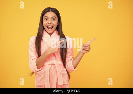 amazed kid in comfortable pajama sit pointing finger on herself on red ...