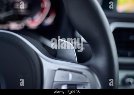 The pad of the automatic gearbox on the steering wheel of a luxury car ...