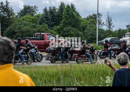 People look at a procession of motorcycles along the highway. Hundreds ...