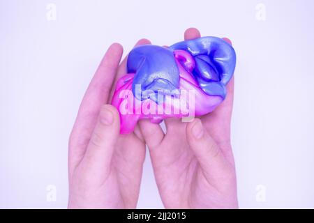 Two-color blue and pink slime in someone hands on a white background ...