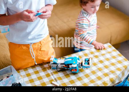 Kid collects robot from plastics details and programmed on tablet ...