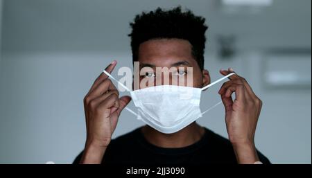 African person removing mask feeling relief Stock Photo - Alamy