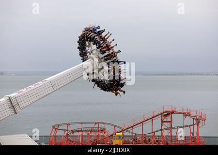 A pendulum ride gondola mid air with people hanging upside down with ...