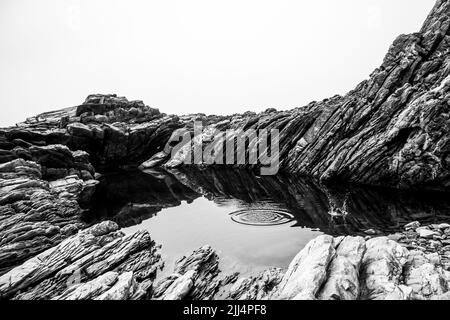 Skipping rocks on a sheltered, calm rock pool among the tilted, jagged ...
