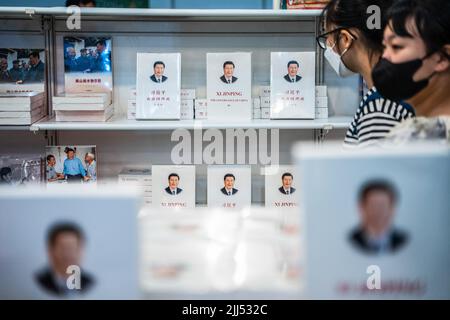 People wearing masks walk by books of Chinese President Xi Jinping's ...