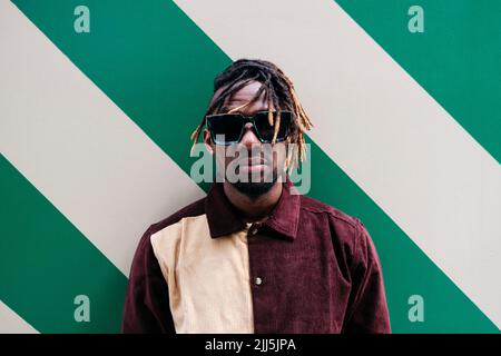 Afro man with dreadlocks wearing striped t-shirt standing over isolated ...
