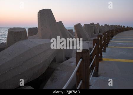 Coastal concrete fortification along a pier in the sea during sunset ...