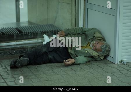 Homeless man in ragged clothes eating a meal standing as his benefactor ...