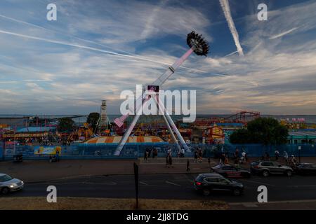 A pendulum ride gondola mid air with people hanging upside down with ...