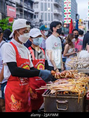 People Grilled squid on a cast iron grill over a charcoal grill ...