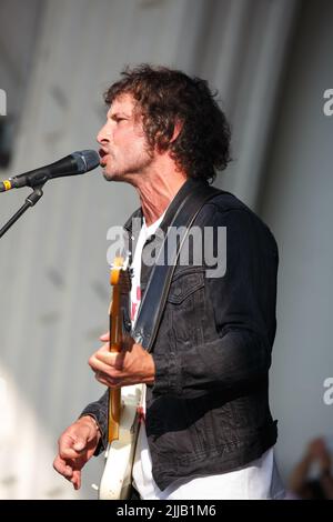 Sam Roberts plays guitar and sings on stage wearing a denim jacket and ...